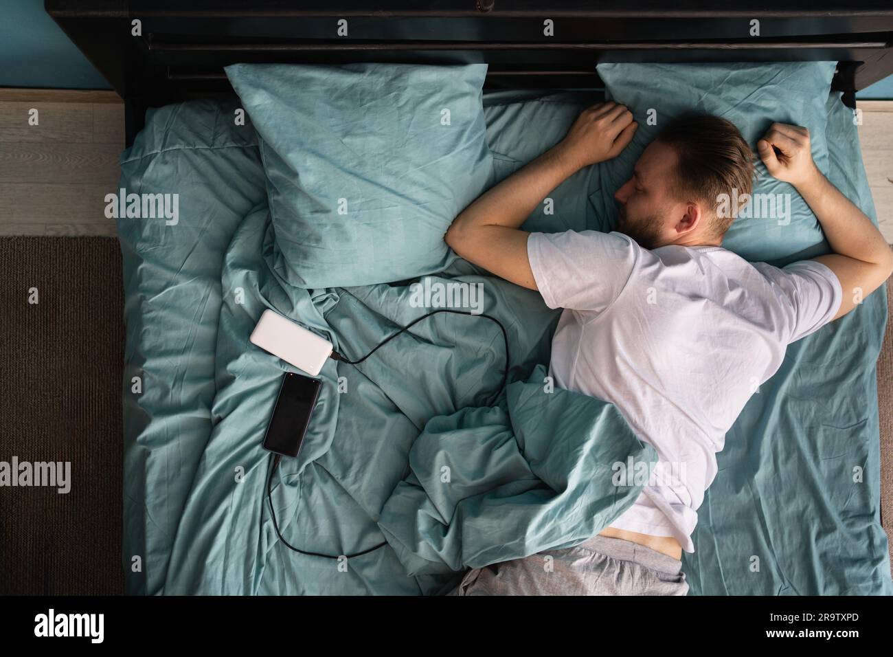 Top view of millennial man sleeping on the bed and turning off ...