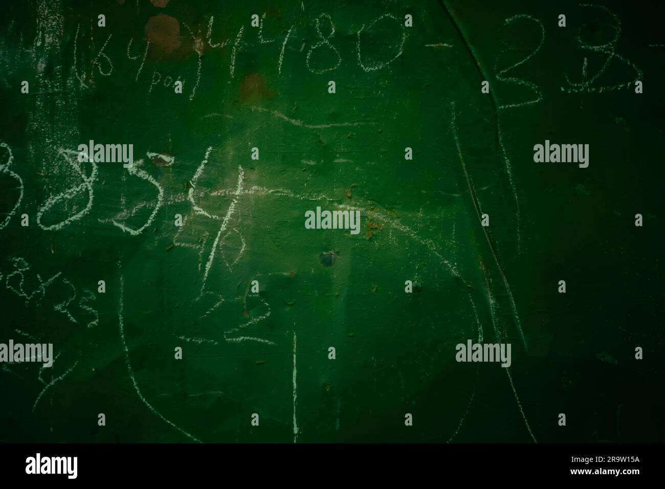 An old peeled green production board with numbers written in chalk ...