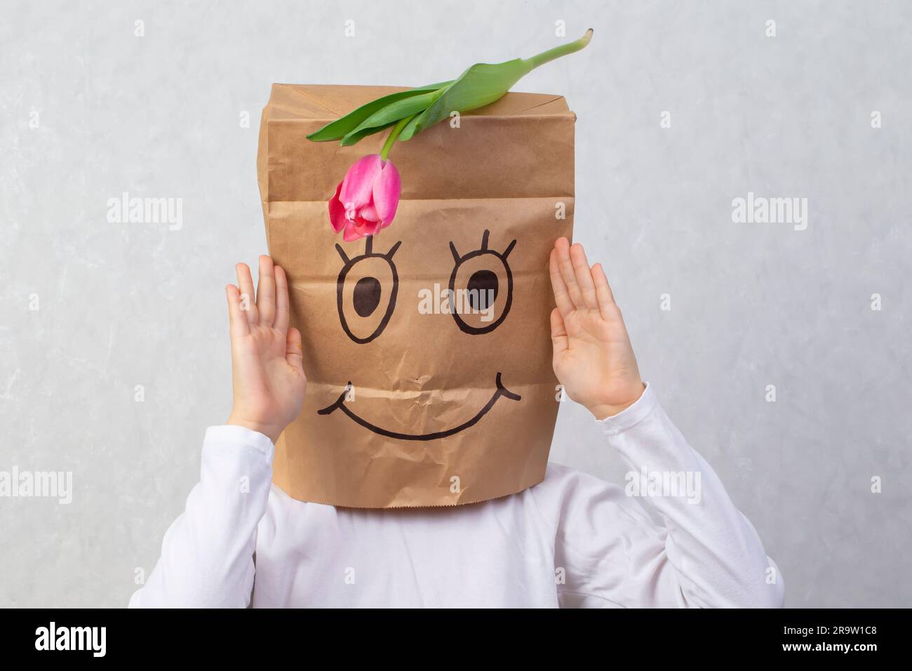 The boy has a cardboard box above his head with a funny smiley face ...
