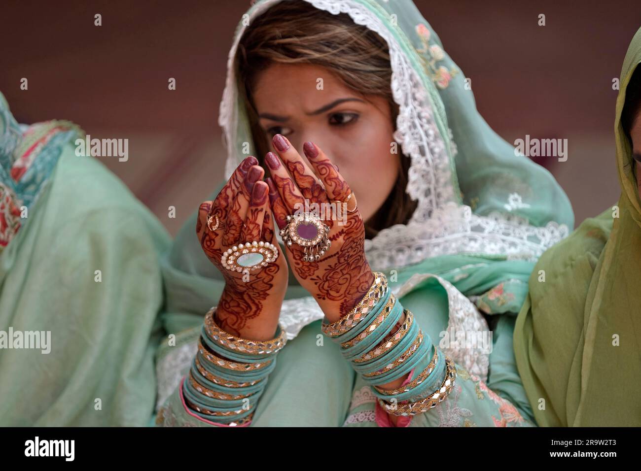 A woman has her hands painted with traditional henna as she attends Eid ...