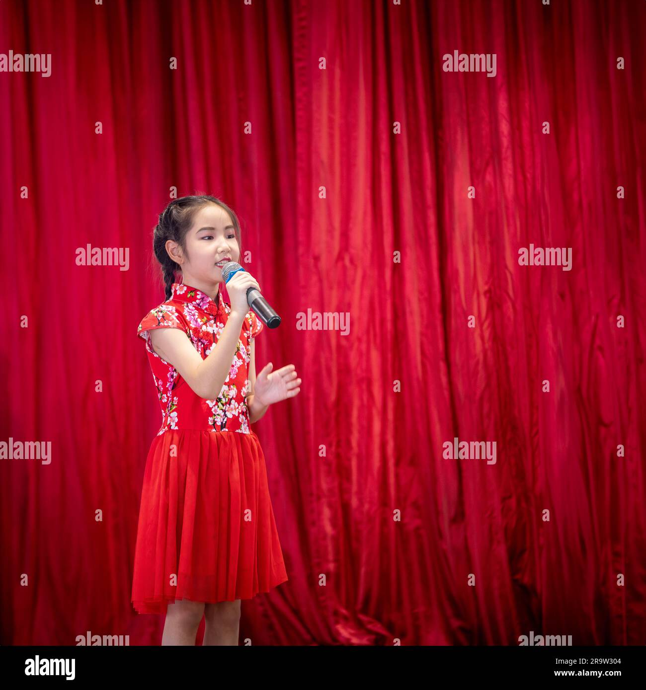 The Asian kid girl sing a song on stage at her school activity day ...