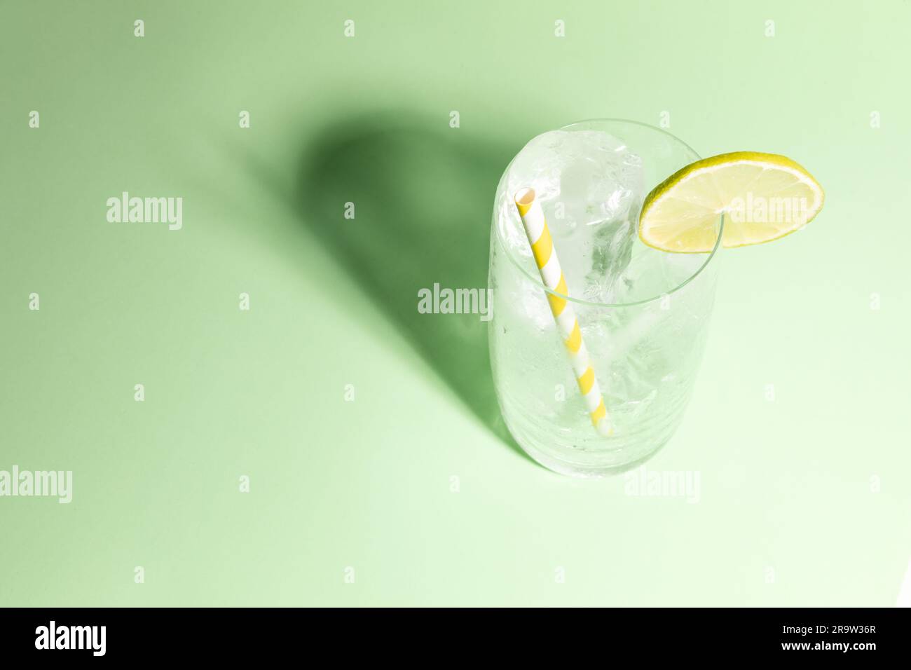 Cold glass full of ice with a lime, ready to serve light green with ...