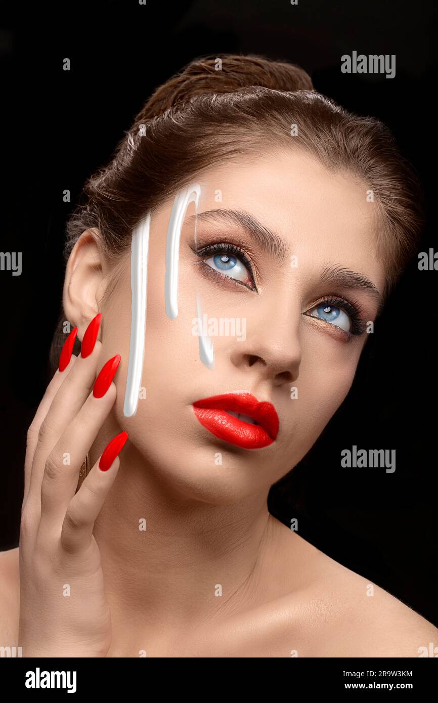 Face cream flows down the girl's skin and red lips. Skin care concept ...