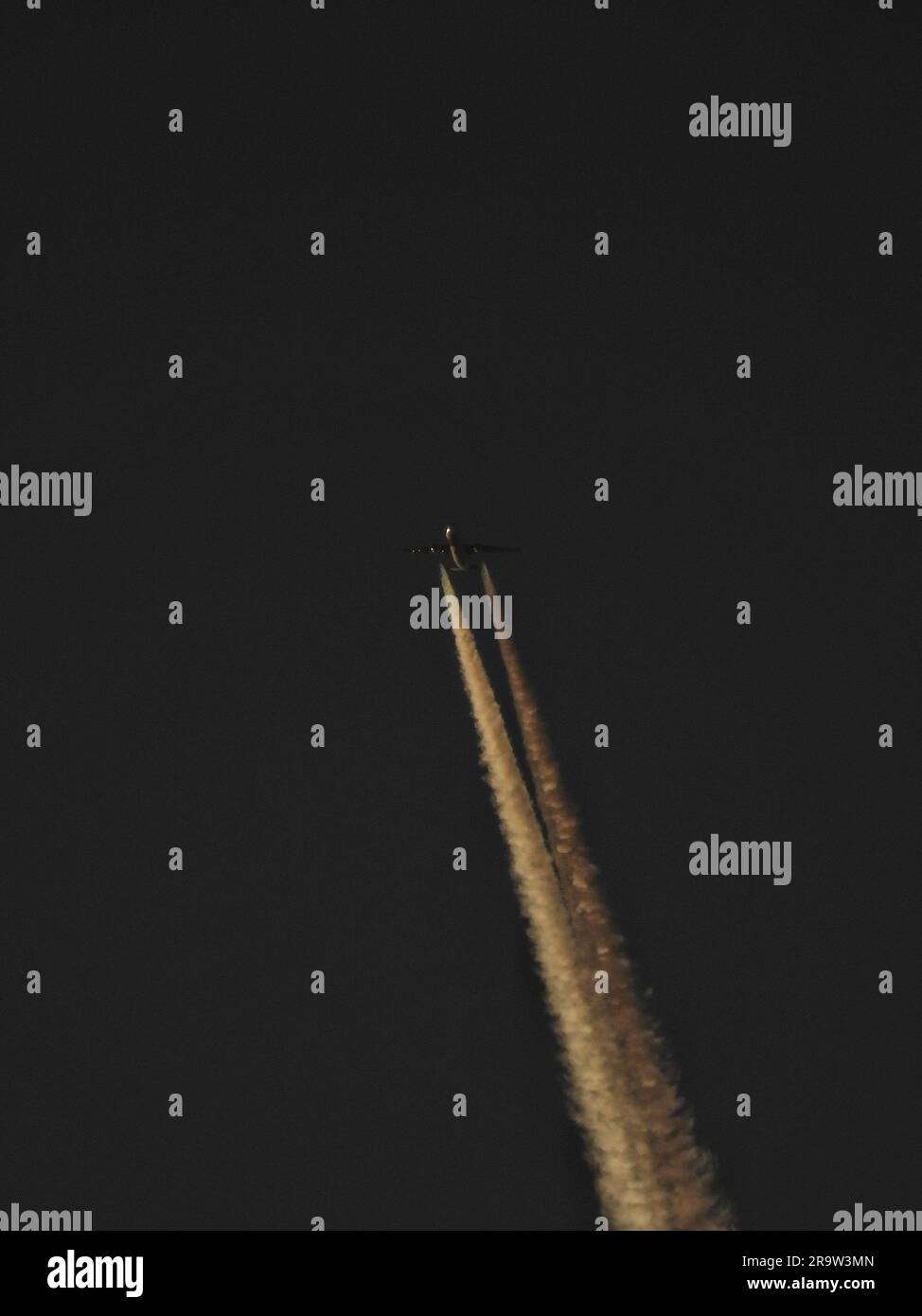 An airplane flying through a night sky, with white smoke emanating from ...
