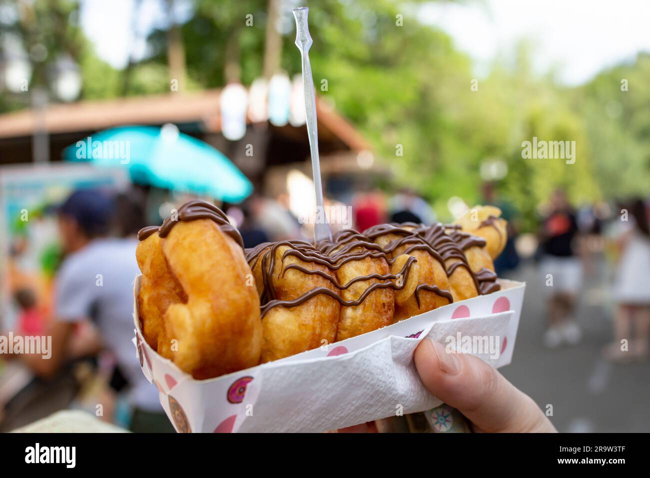 Woman hand holding Ring shaped donuts with chocolate topping in a white ...