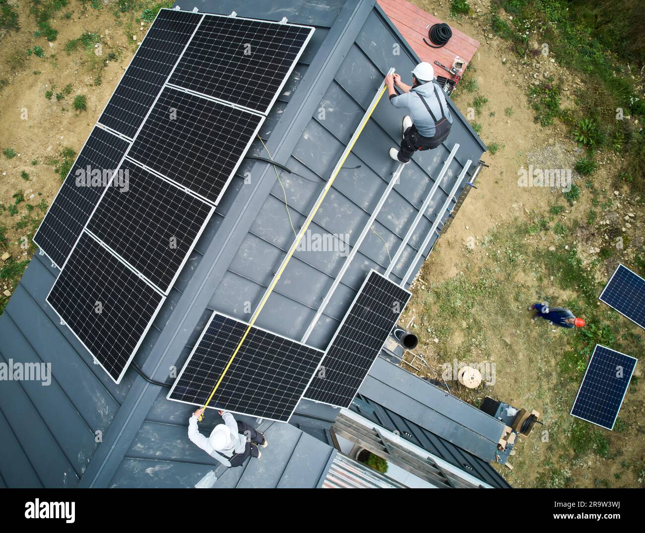 Engineers measuring photovoltaic solar panels with tape measure. Aerial ...