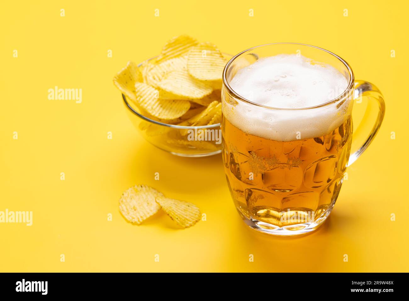 A tempting snack of beer and chips on a vibrant yellow background with ...