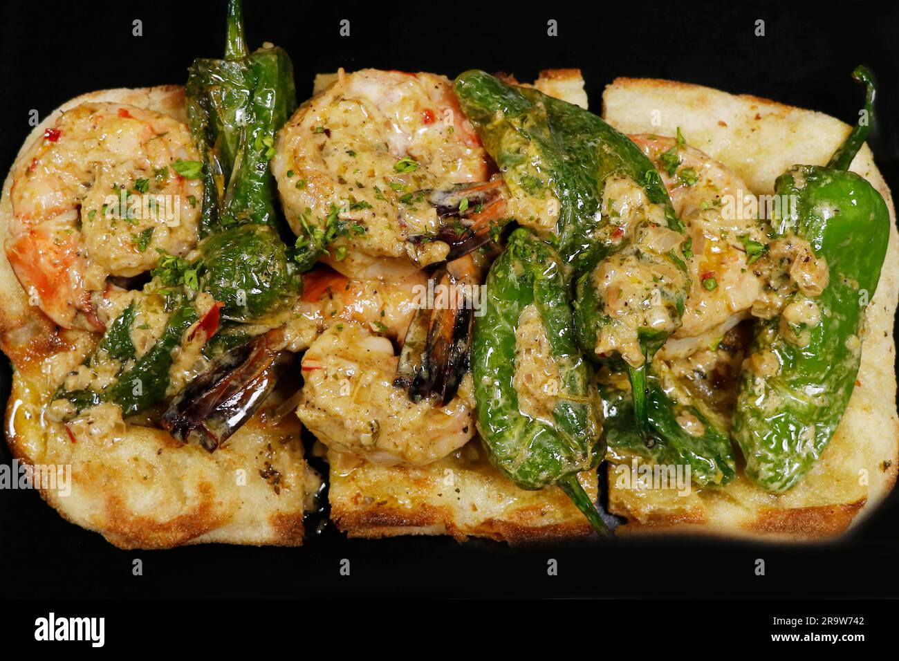 sauteed king tiger prawns with padron pepper in butter sauce and crispy bread Stock Photo - Alamy