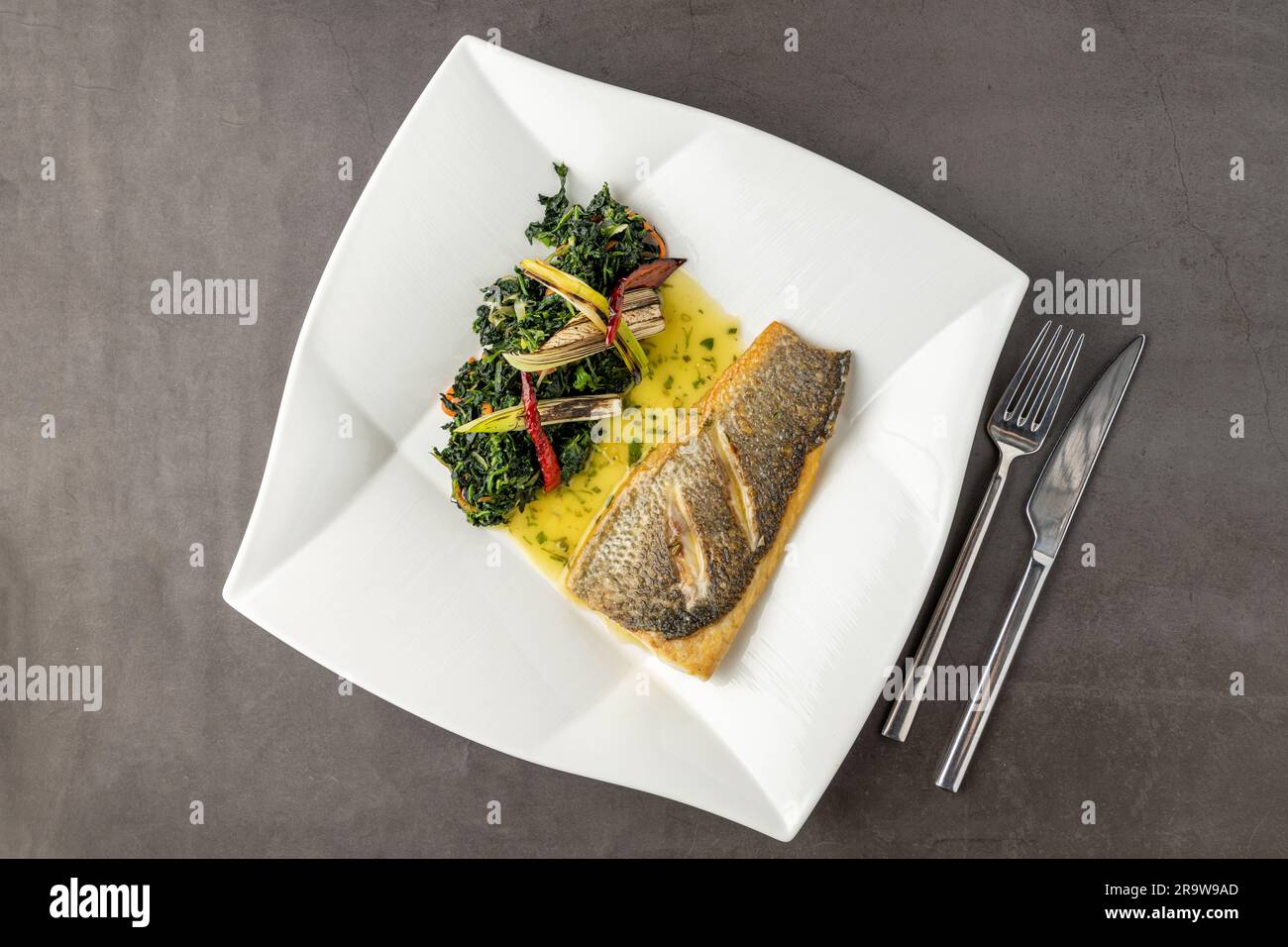Grilled sea bass fillet served with garnishes in a fine dining ...