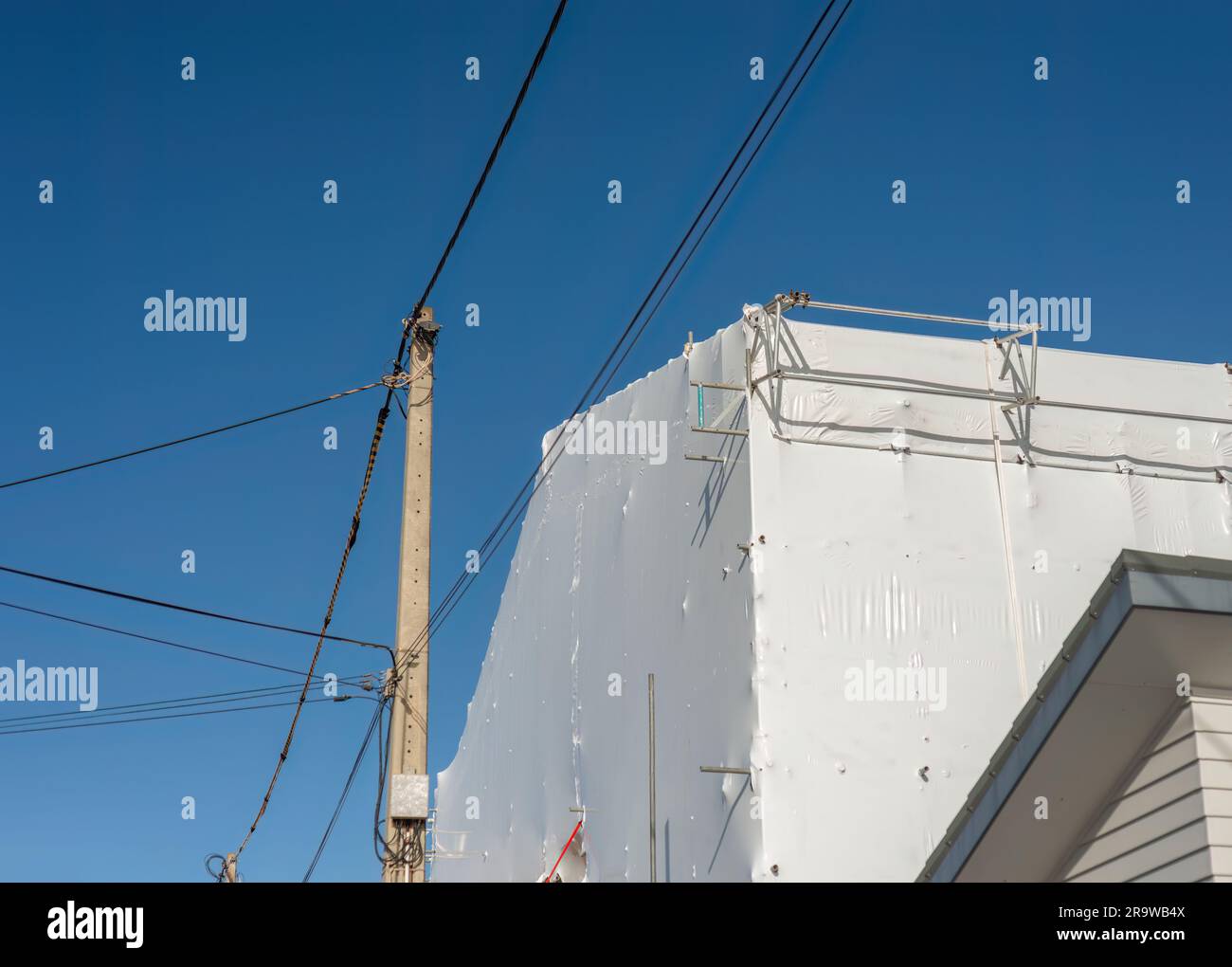 Residential house under repair with metal scaffolding and white sheet ...