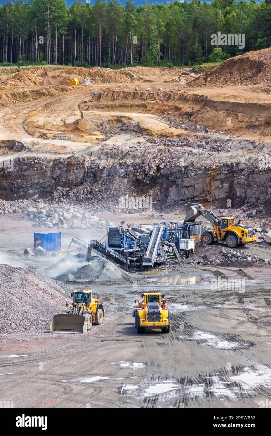 Loader tipping stones in a crushing plant in a quarry Stock Photo - Alamy