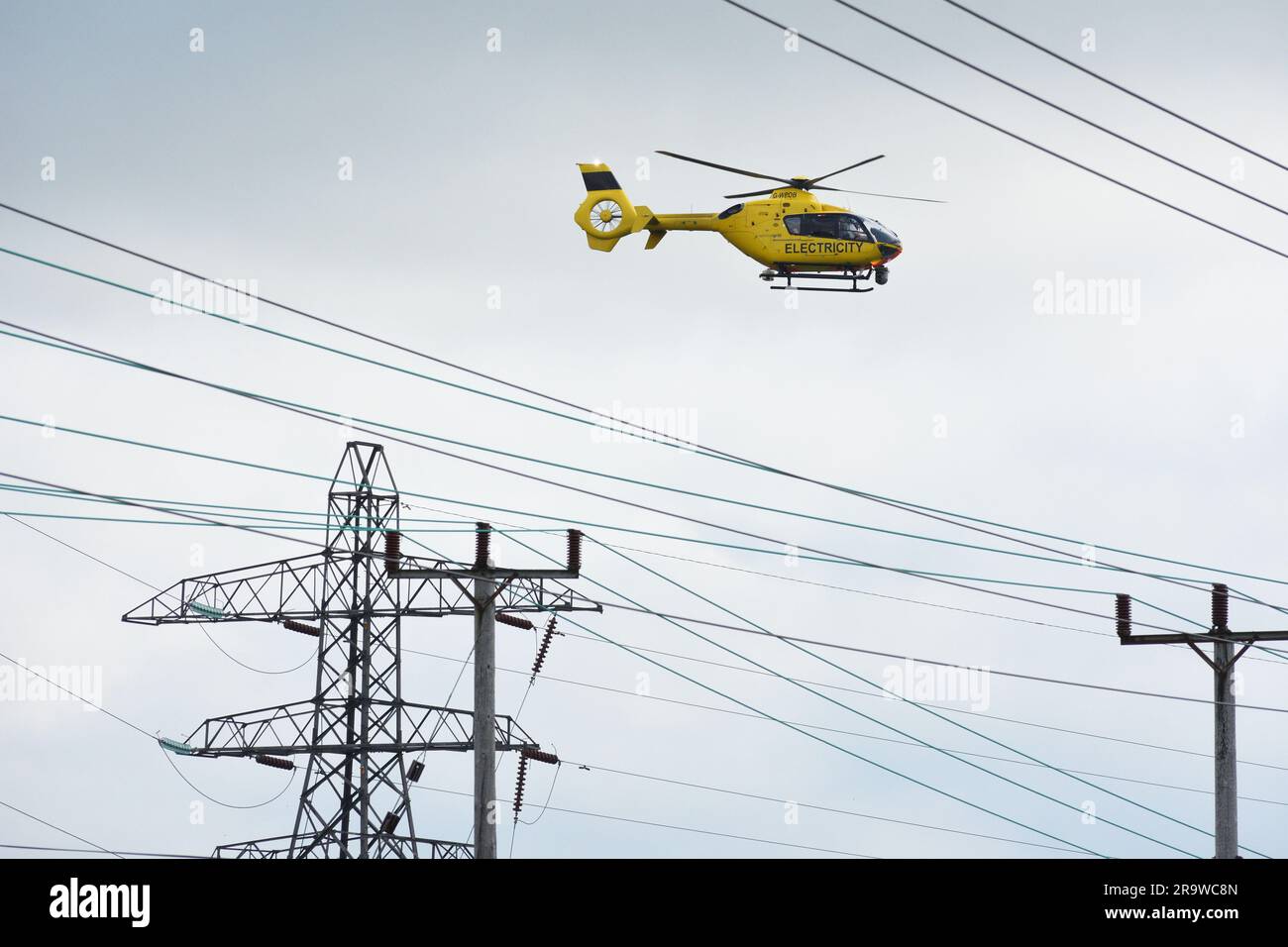 Yellow Airbus Helicopter close to high power pylon lines Stock Photo ...