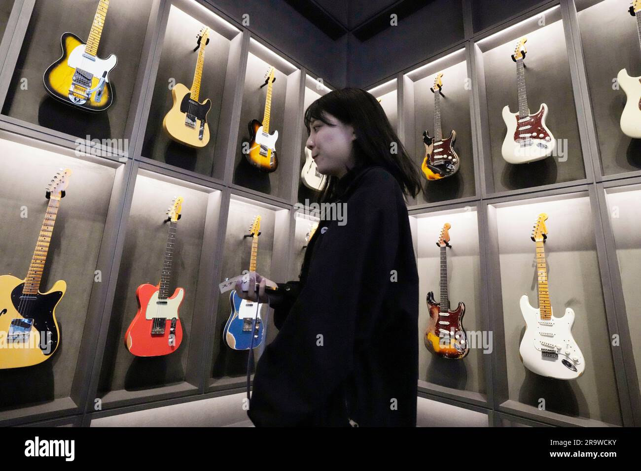 A staff member walks past Fender guitars on display at the opening ...