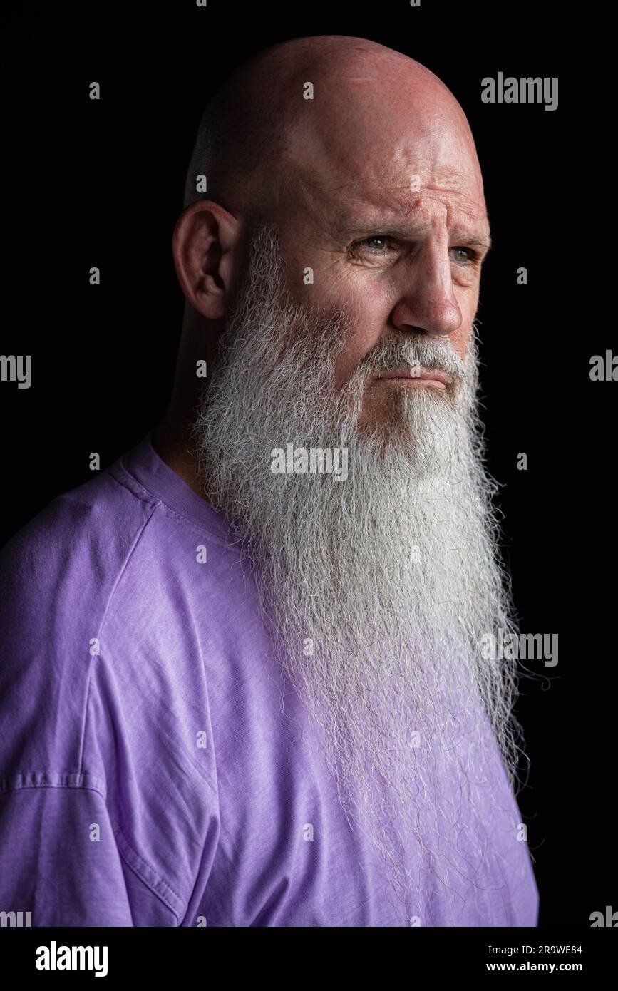 Portrait of man with long gray beard wearing purple t-shirt close-up ...