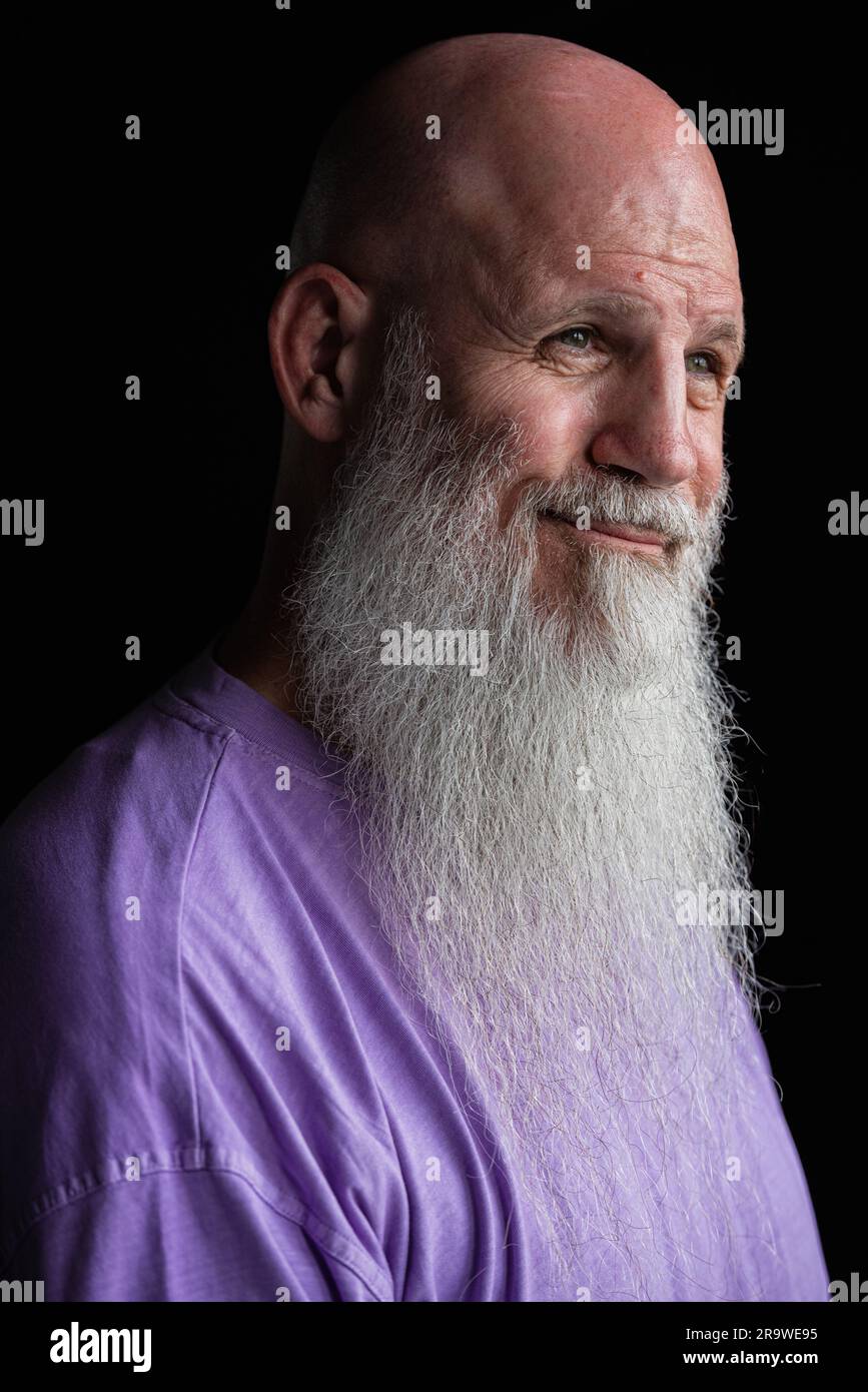 Portrait of man with long gray beard wearing purple t-shirt close-up ...