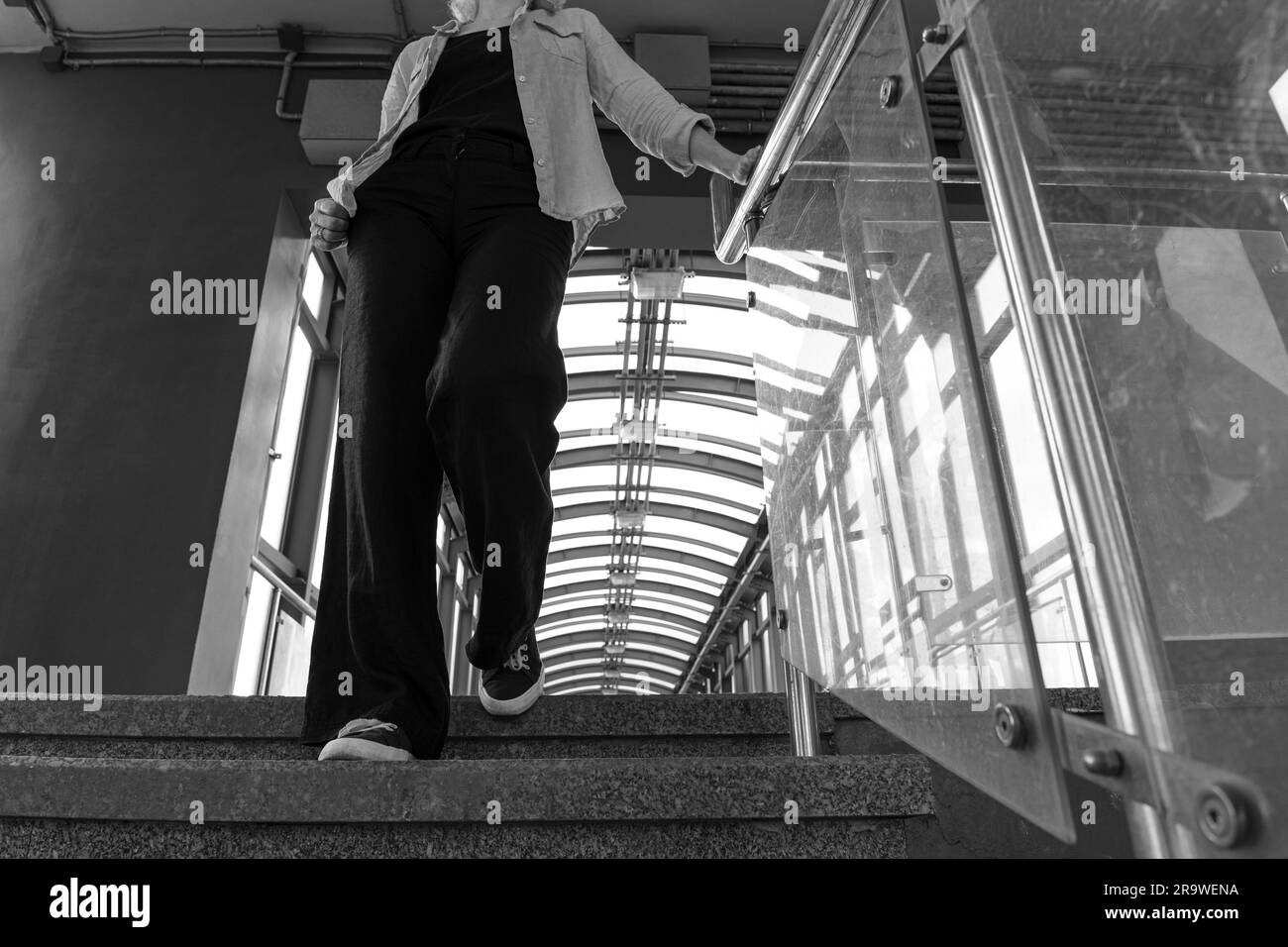woman walking down the stairs holding onto the railing. a woman walks ...
