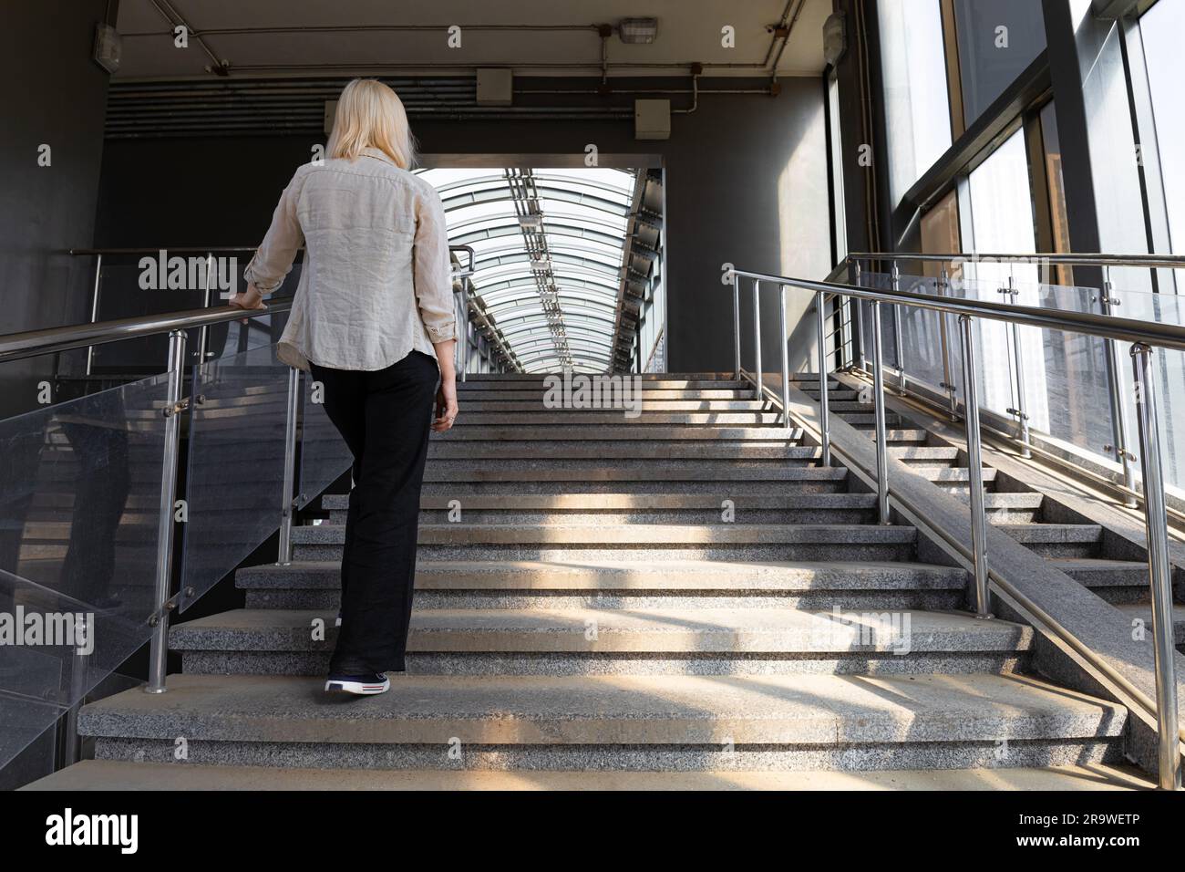 woman climbing the stairs holding on to the railing Stock Photo - Alamy