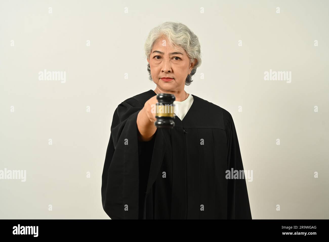 Strict senior female judge dressed in robe gown uniform with gavel ...