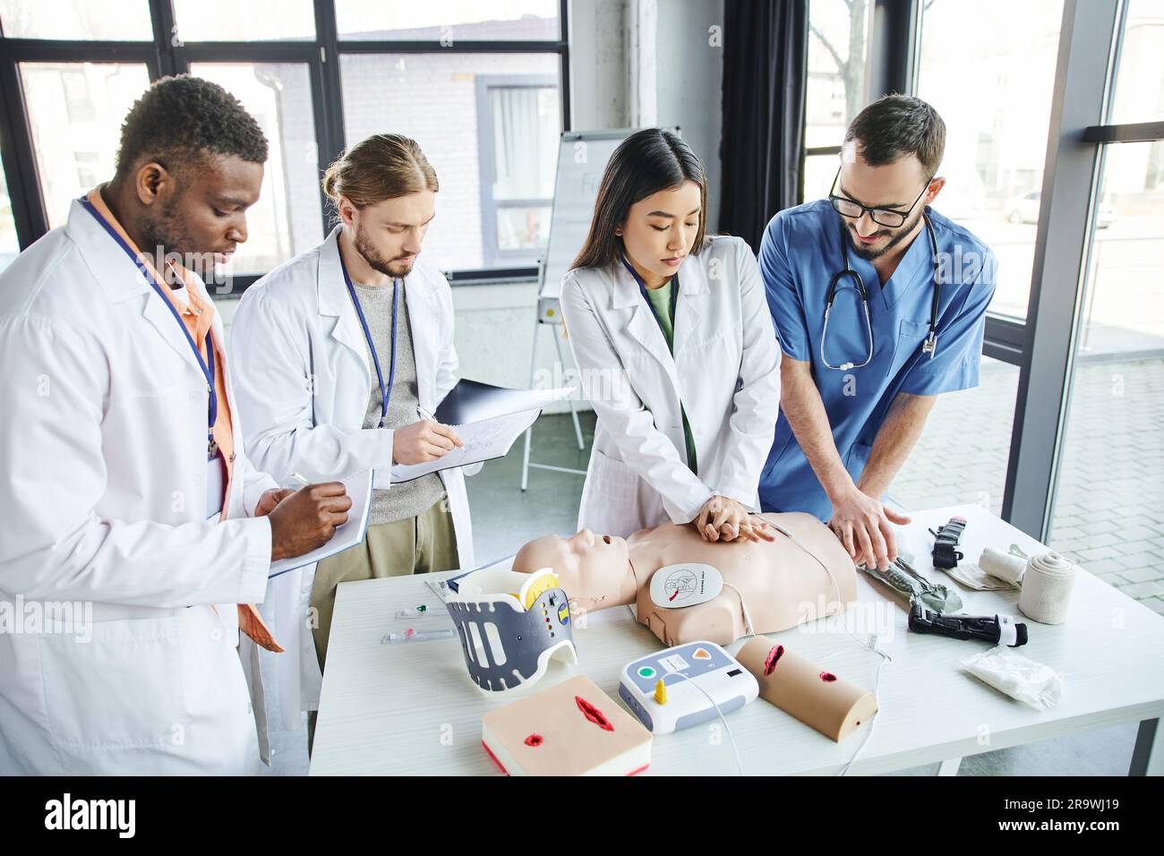first aid seminar, multiethnic students in white coats writing near ...