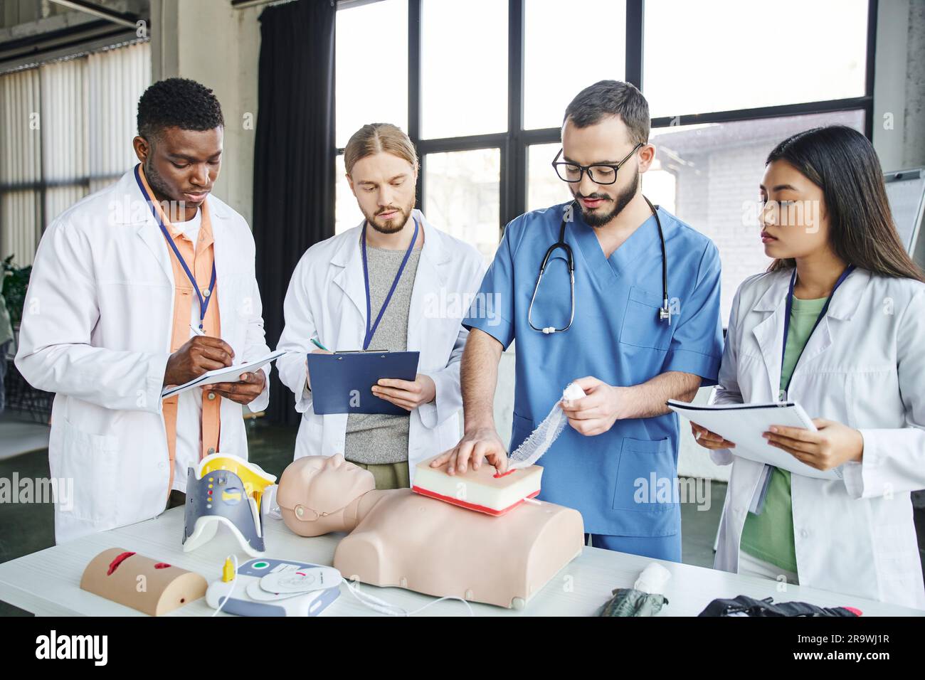 multicultural students in white coats writing on clipboards and looking ...