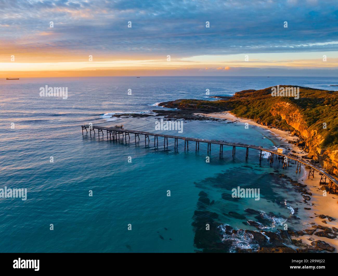 Sunrise seascape with cloud filled sky and the old coal loading jetty ...