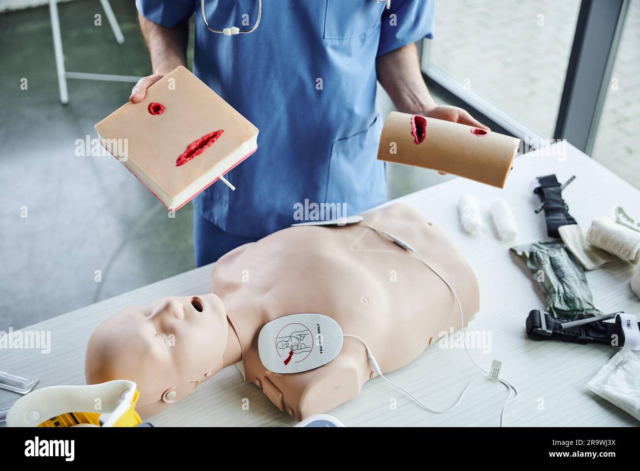 partial view of medical instructor standing with wound care simulator near CPR manikin with ...
