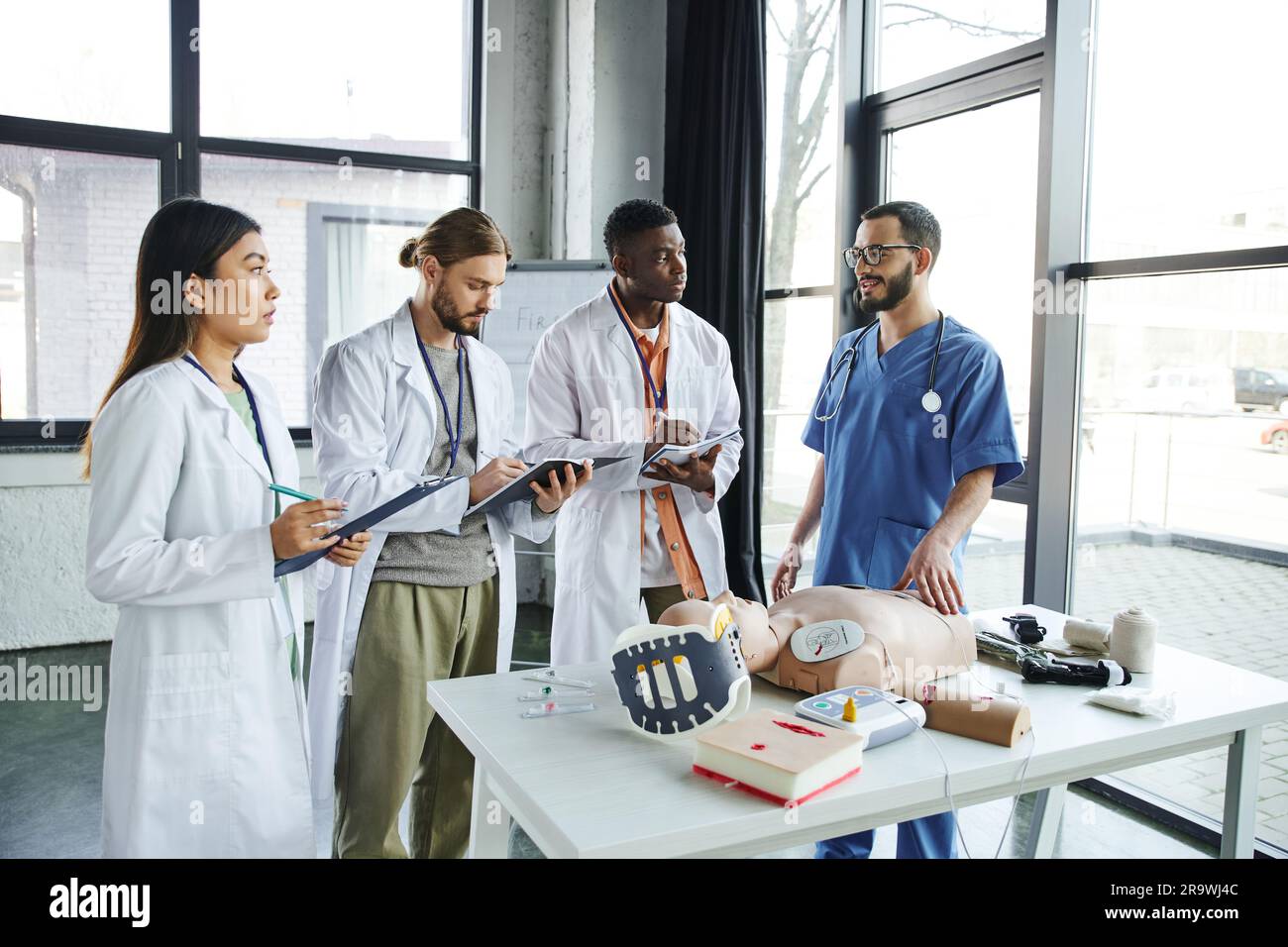professional paramedic talking to multiethnic students writing near CPR ...