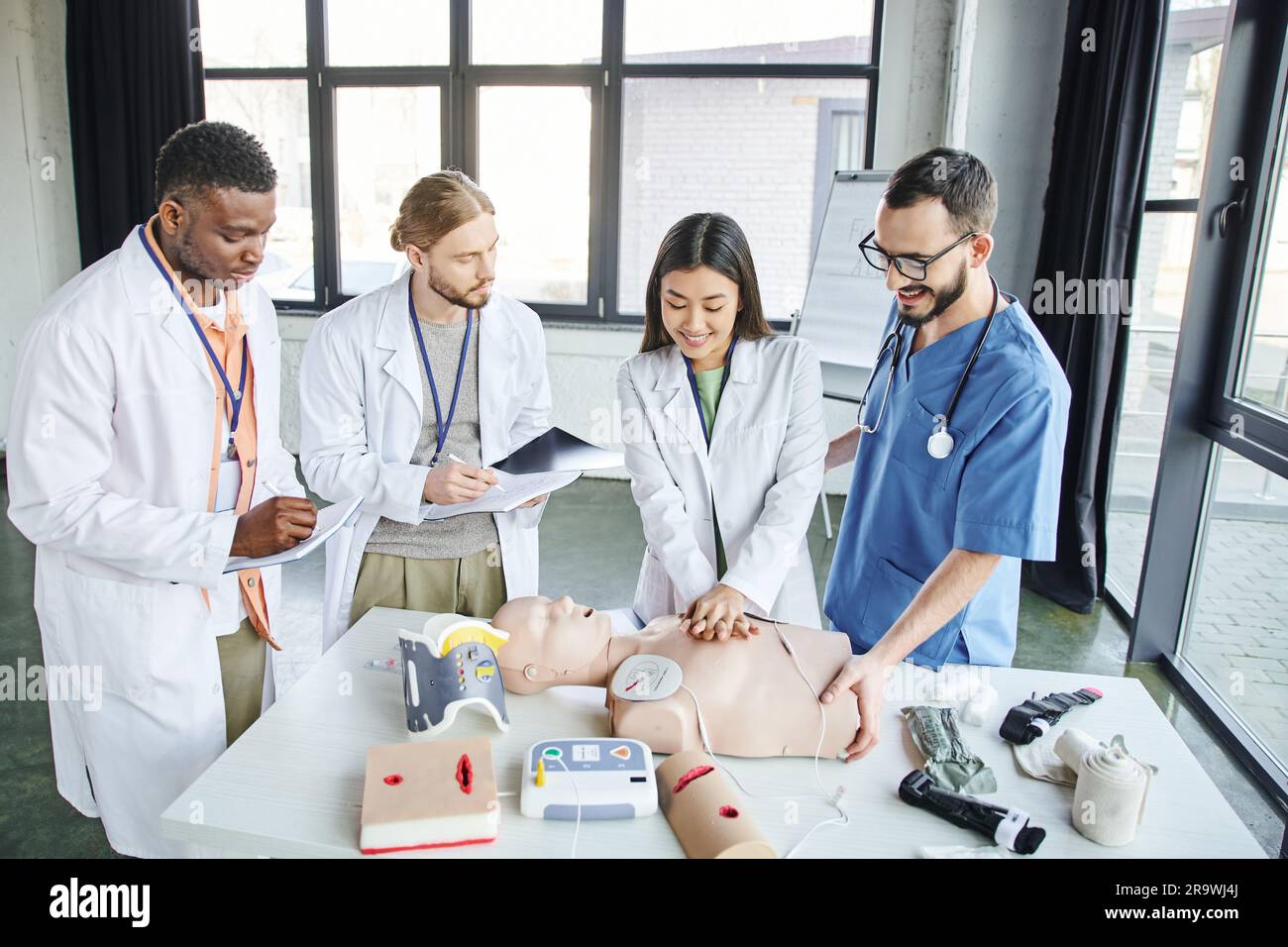 first aid training, cheerful asian woman practicing chest compressions on CPR manikin near ...