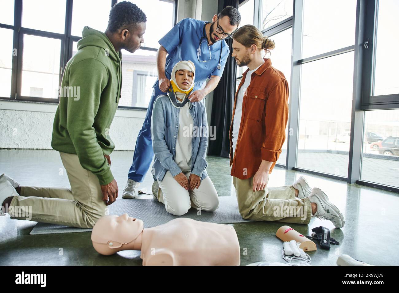 first aid training, interracial men looking at medical instructor putting neck brace on asian ...