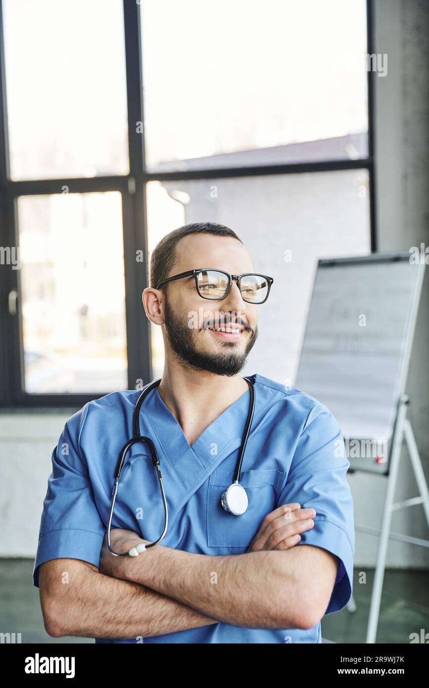 happy bearded medical instructor in eyeglasses, blue uniform and ...