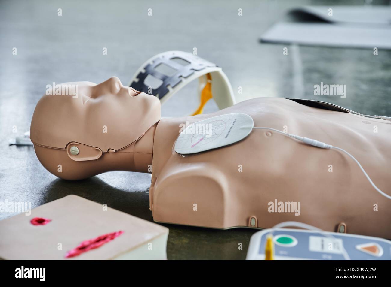 CPR manikin near automated external defibrillator, wound care simulator and neck brace on ...