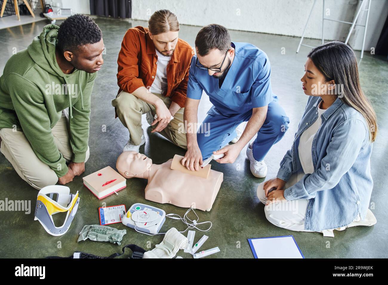first aid seminar, high angle view of paramedic tamponing wound on simulator with bandage near ...