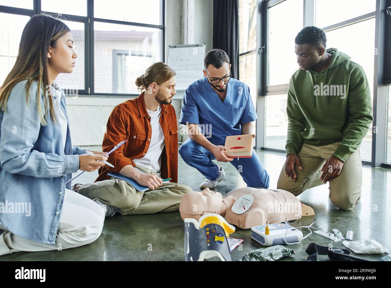 professional paramedic showing wound care simulator to multicultural team near CPR manikin ...
