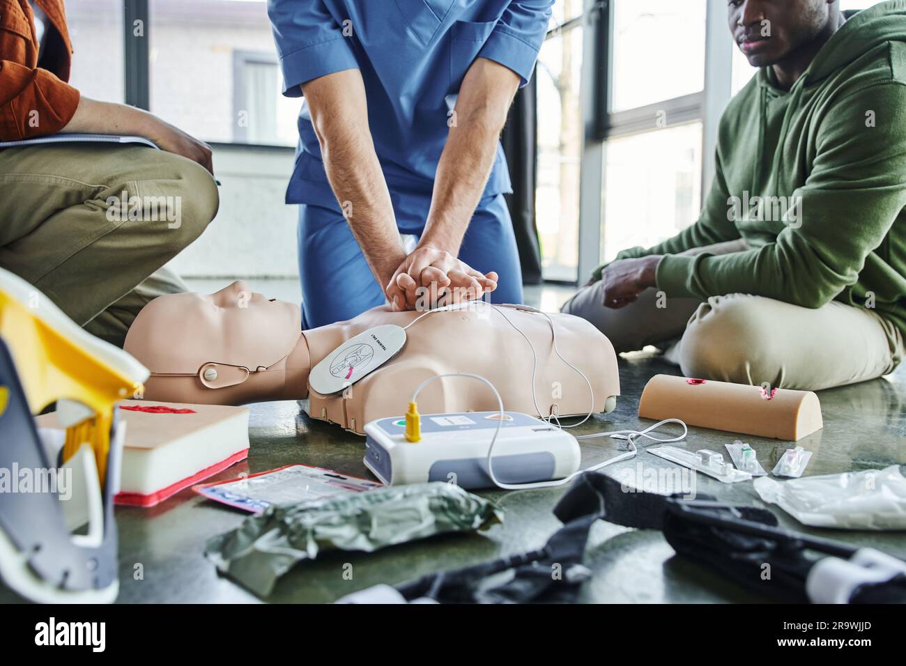 partial view of paramedic doing chest compressions on CPR manikin near ...