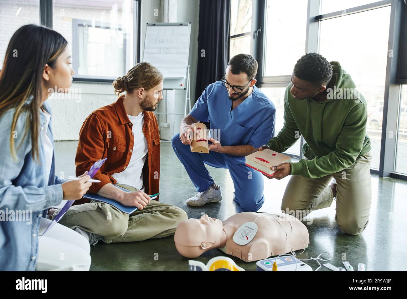 medical instructor and african american man holding wound care simulators near CPR manikin ...
