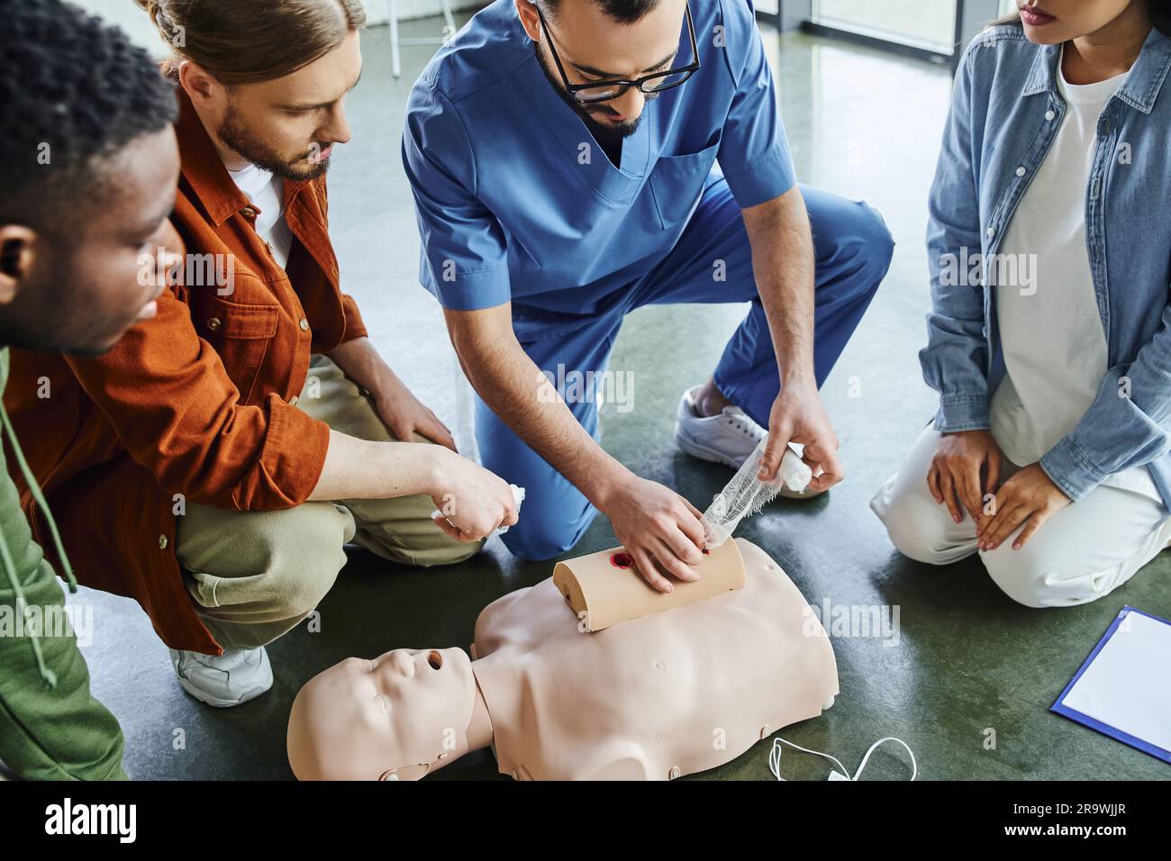 high angle view of professional paramedic tamponing wound on simulator ...