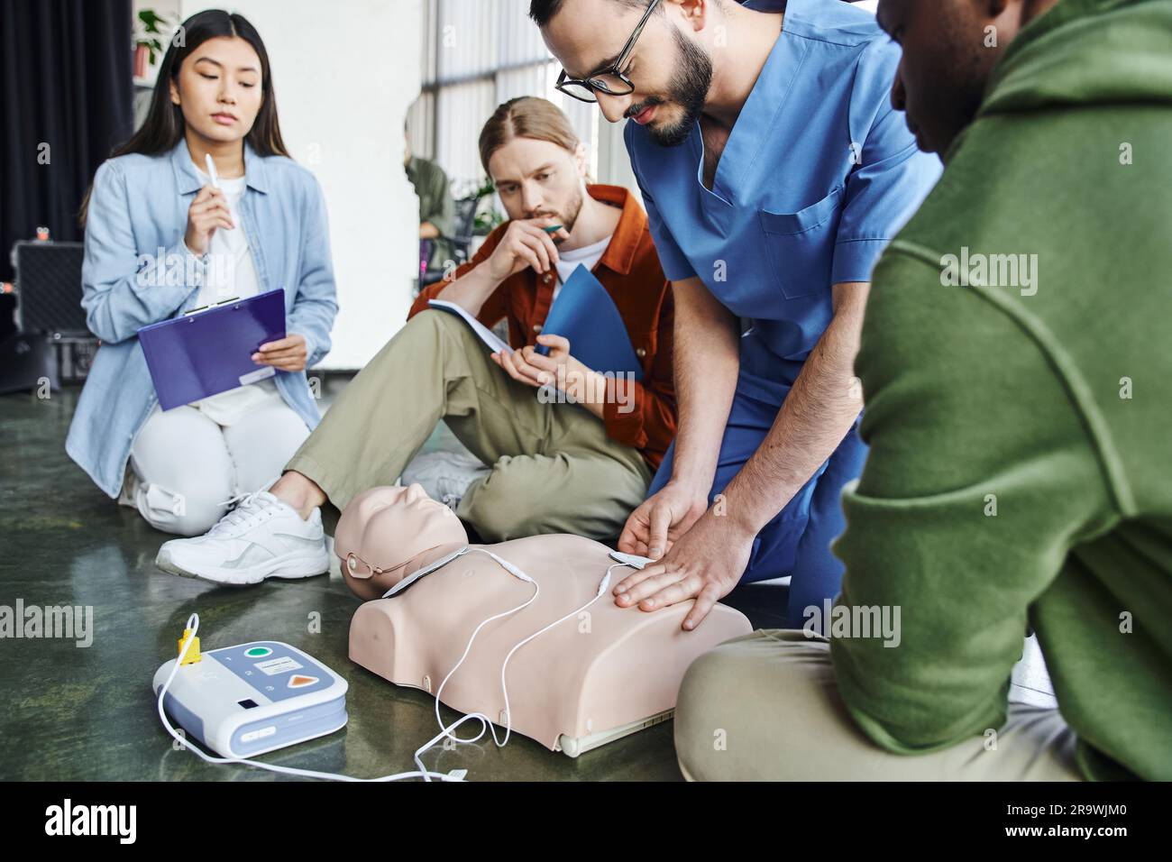 first aid seminar, medical instructor applying defibrillator pads on CPR manikin near ...