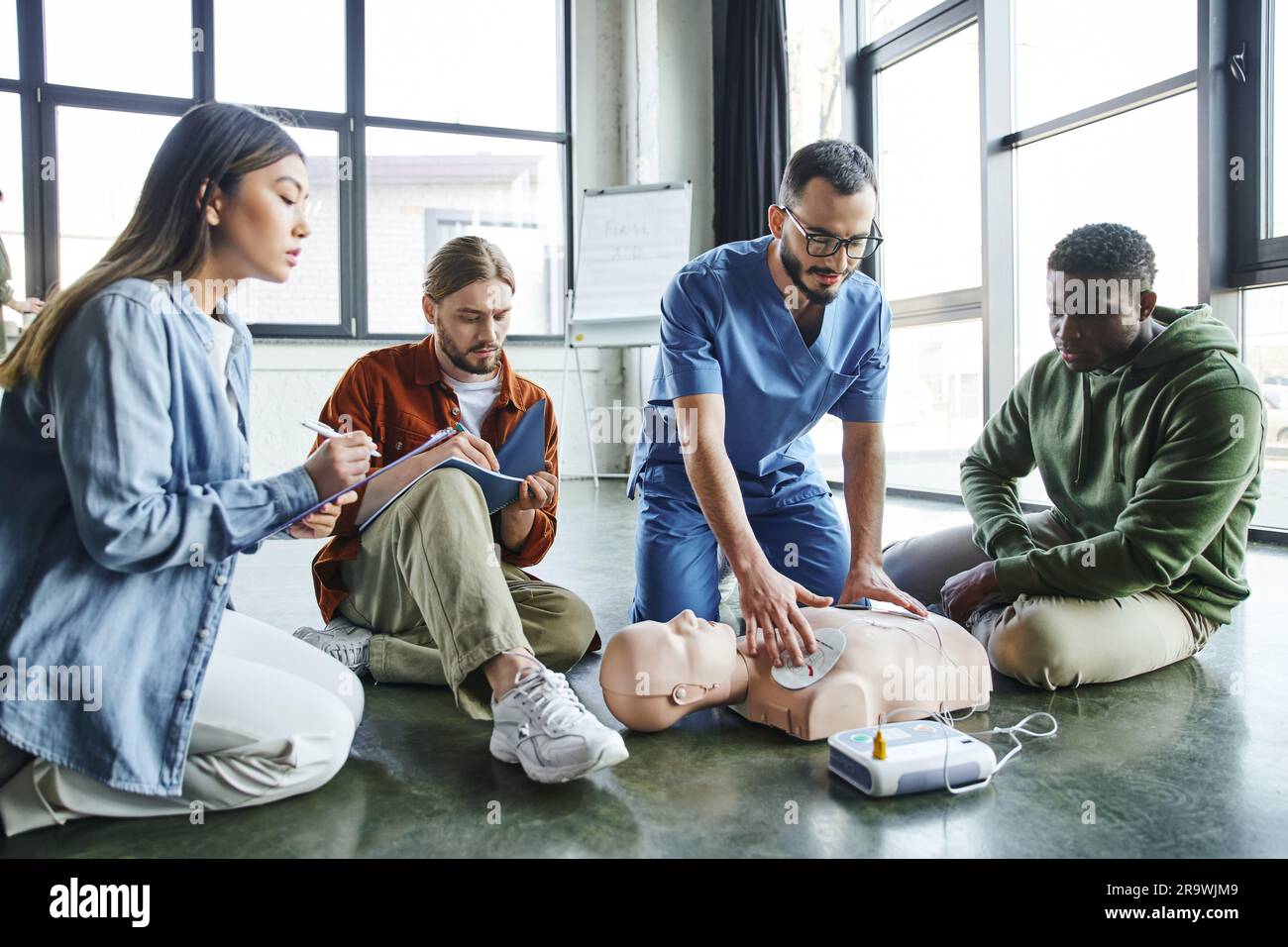 cardiac resuscitation skills, healthcare worker applying defibrillator pads on CPR manikin near ...