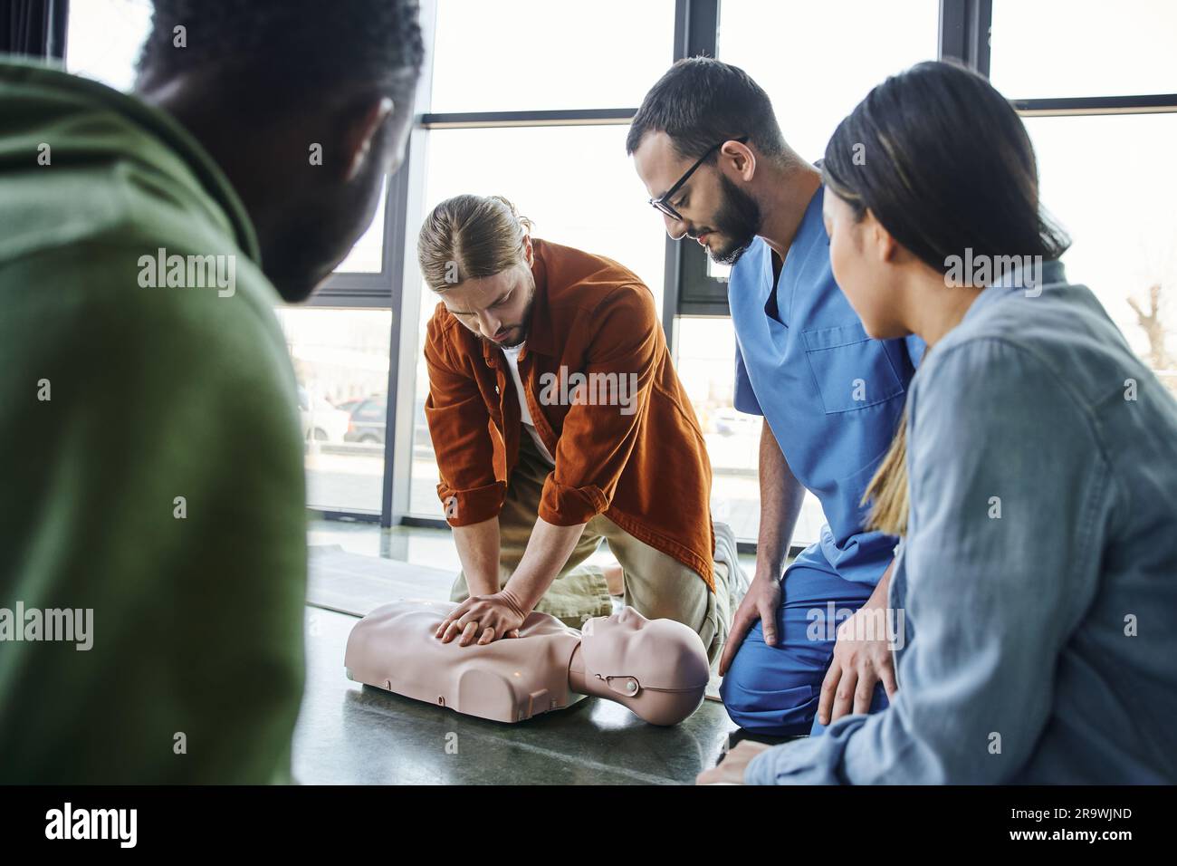 cardiopulmonary resuscitation, young man doing chest compressions on CPR manikin during hands-on ...