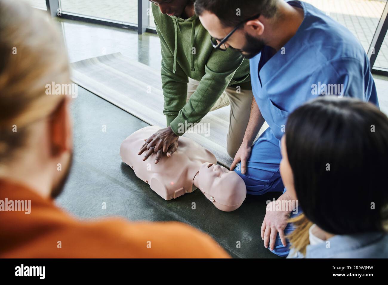 african american man practicing chest compressions and cardiopulmonary resuscitation on CPR ...