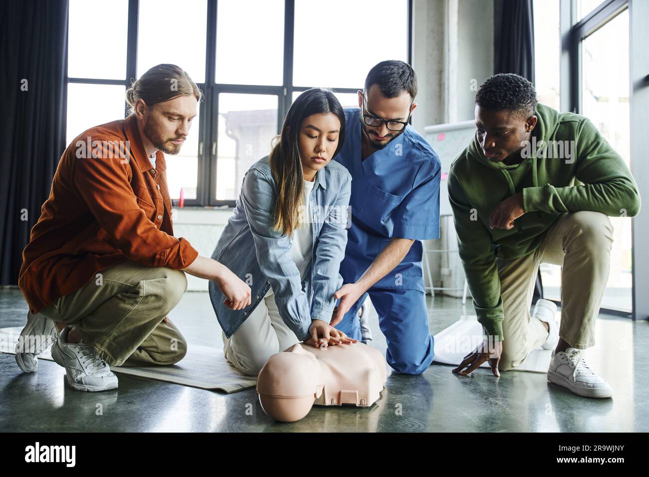 young asian woman doing chest compressions on CPR manikin while ...