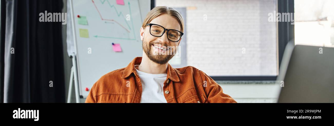 overjoyed bearded businessman in eyeglasses and trendy shirt, with radiant smile, looking at ...