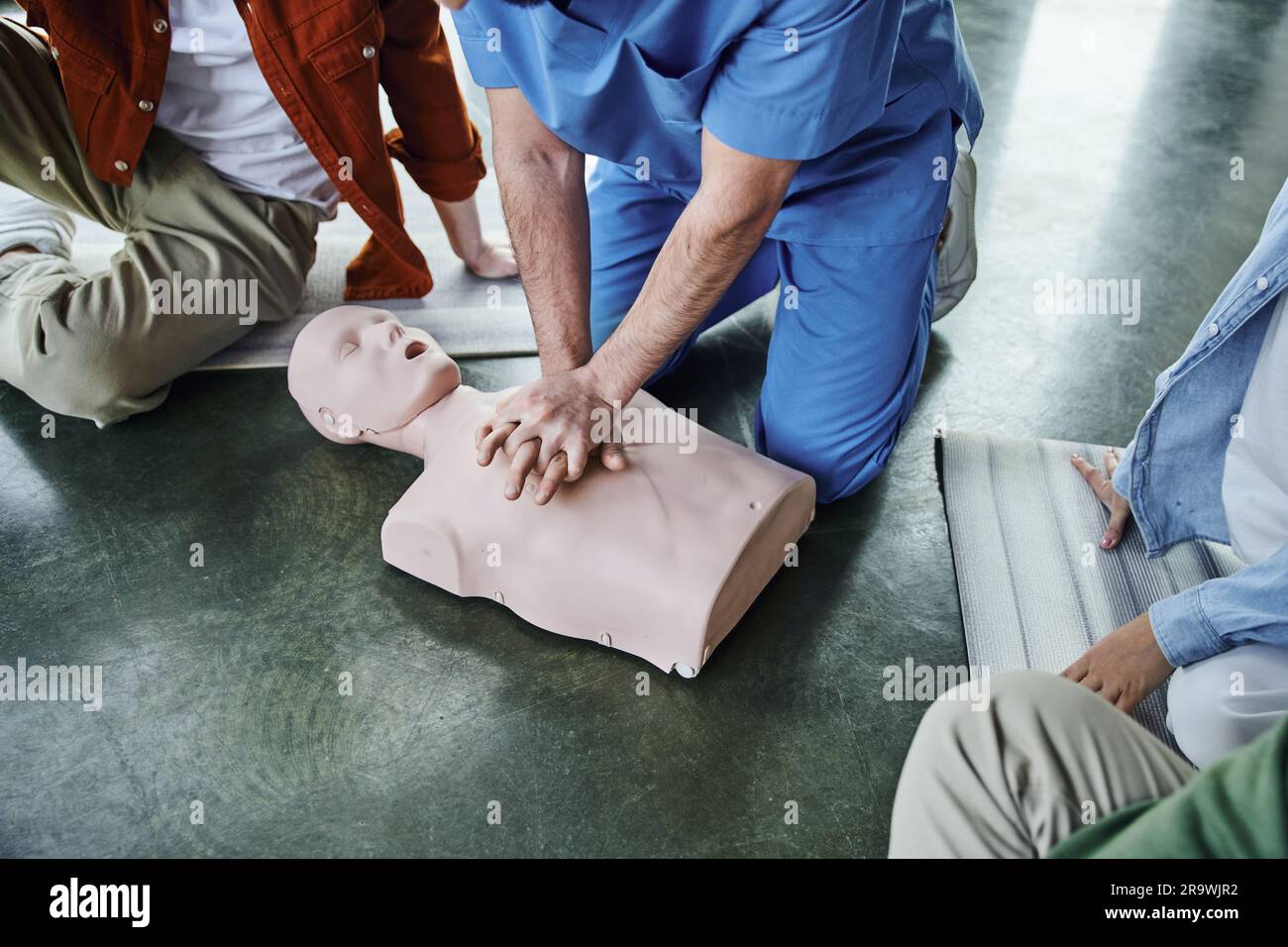 first aid hands-on learning, cropped view of healthcare worker doing chest compressions on CPR ...