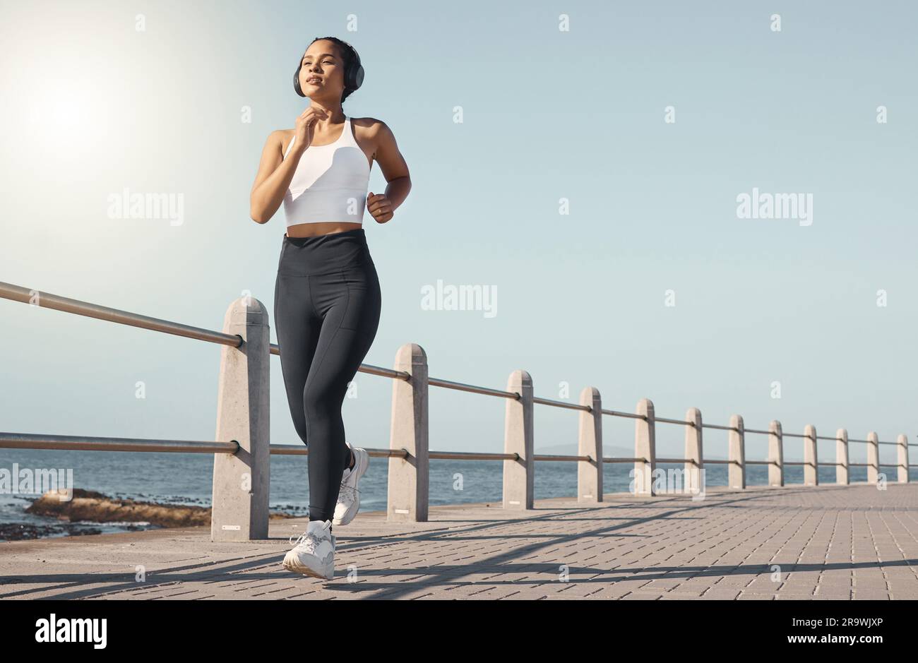 Fitness, woman run at beach and with headphones listening to radio with ...