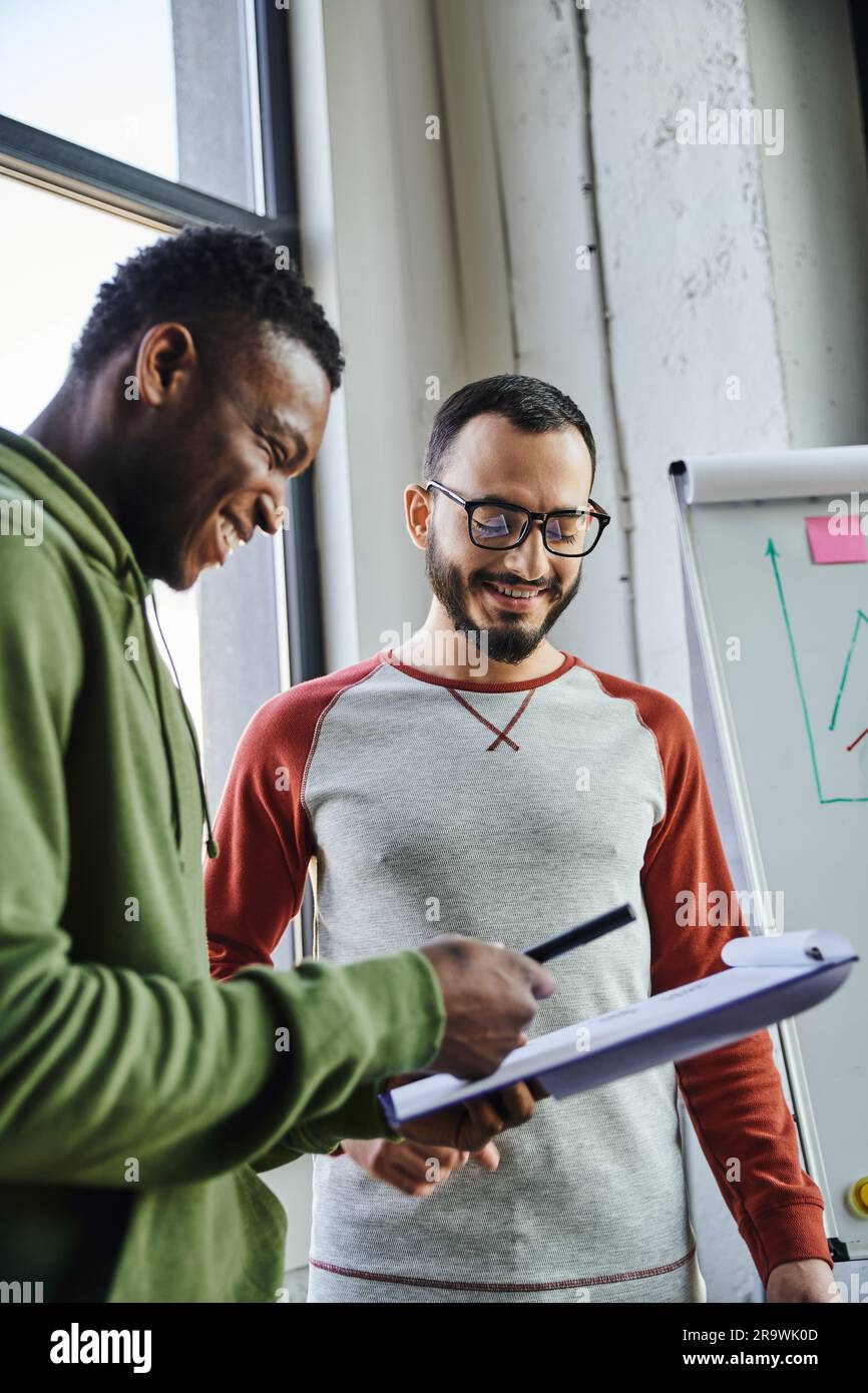 young and cheerful african american entrepreneur showing documents on ...