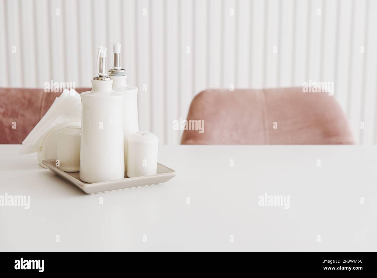 Kitchen stand with spice jars on white wooden table. Salt, pepper, oil ...