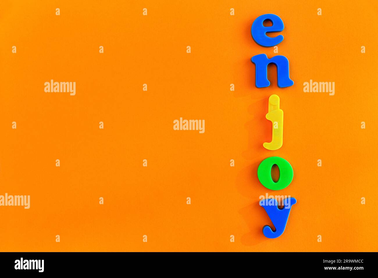 Colourful letters form the word enjoy, vertical arrangement, tabletop ...