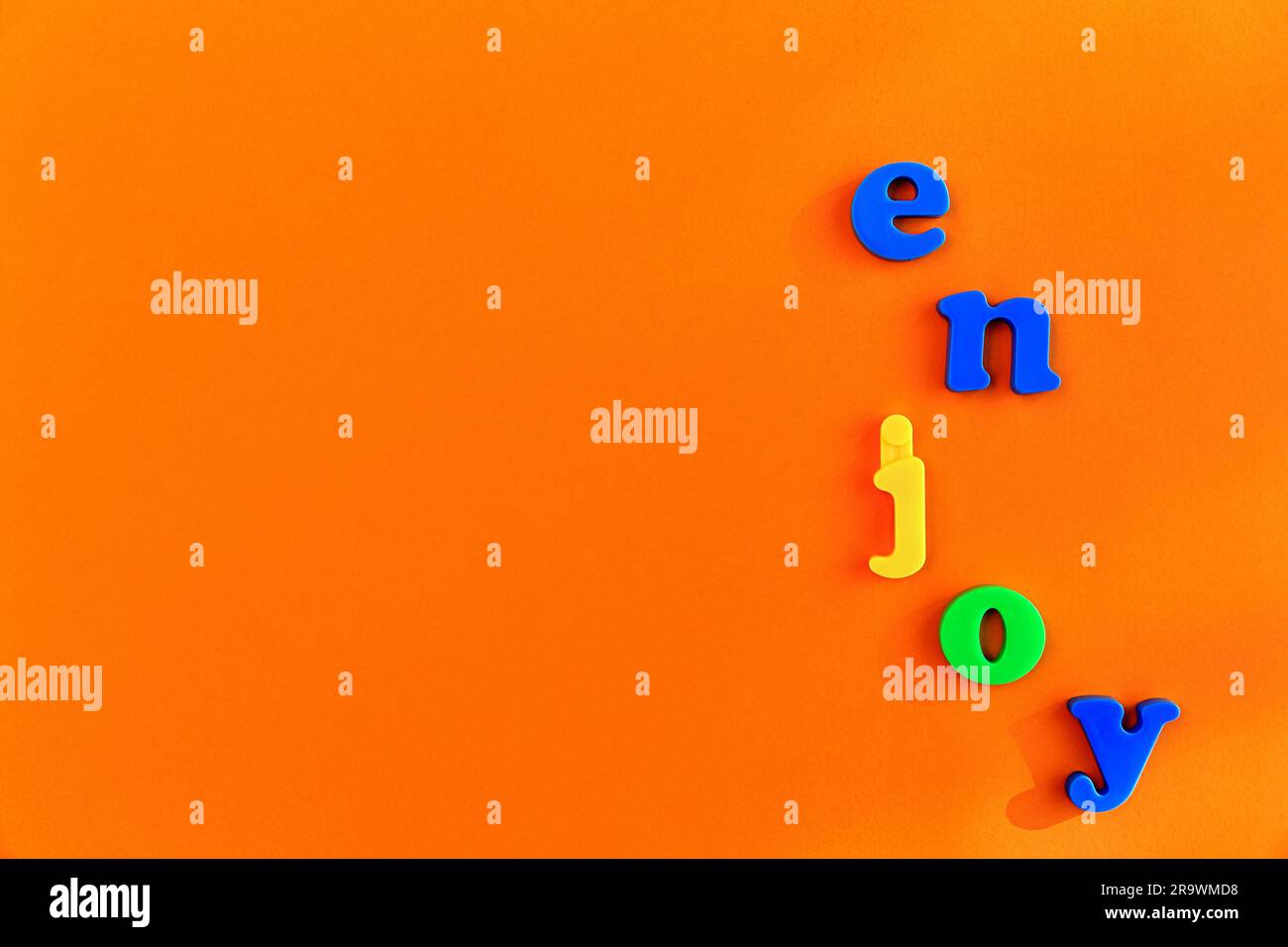 Colourful letters form the word enjoy, vertical arrangement, tabletop ...