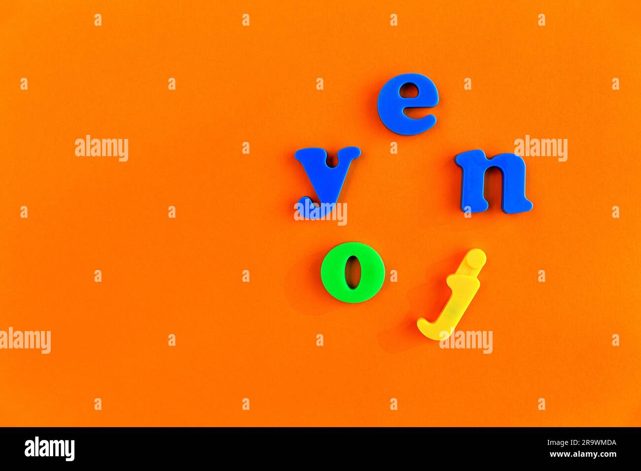 Colourful letters form the word enjoy, circular arrangement, tabletop ...