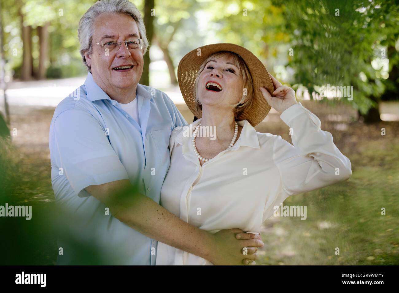 Summery dressed woman with straw hat together with her man laughing in ...